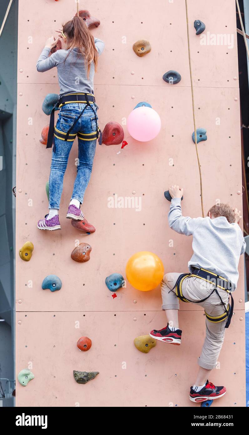 Two children climb the bouldering artificial wall and compete in speed ...