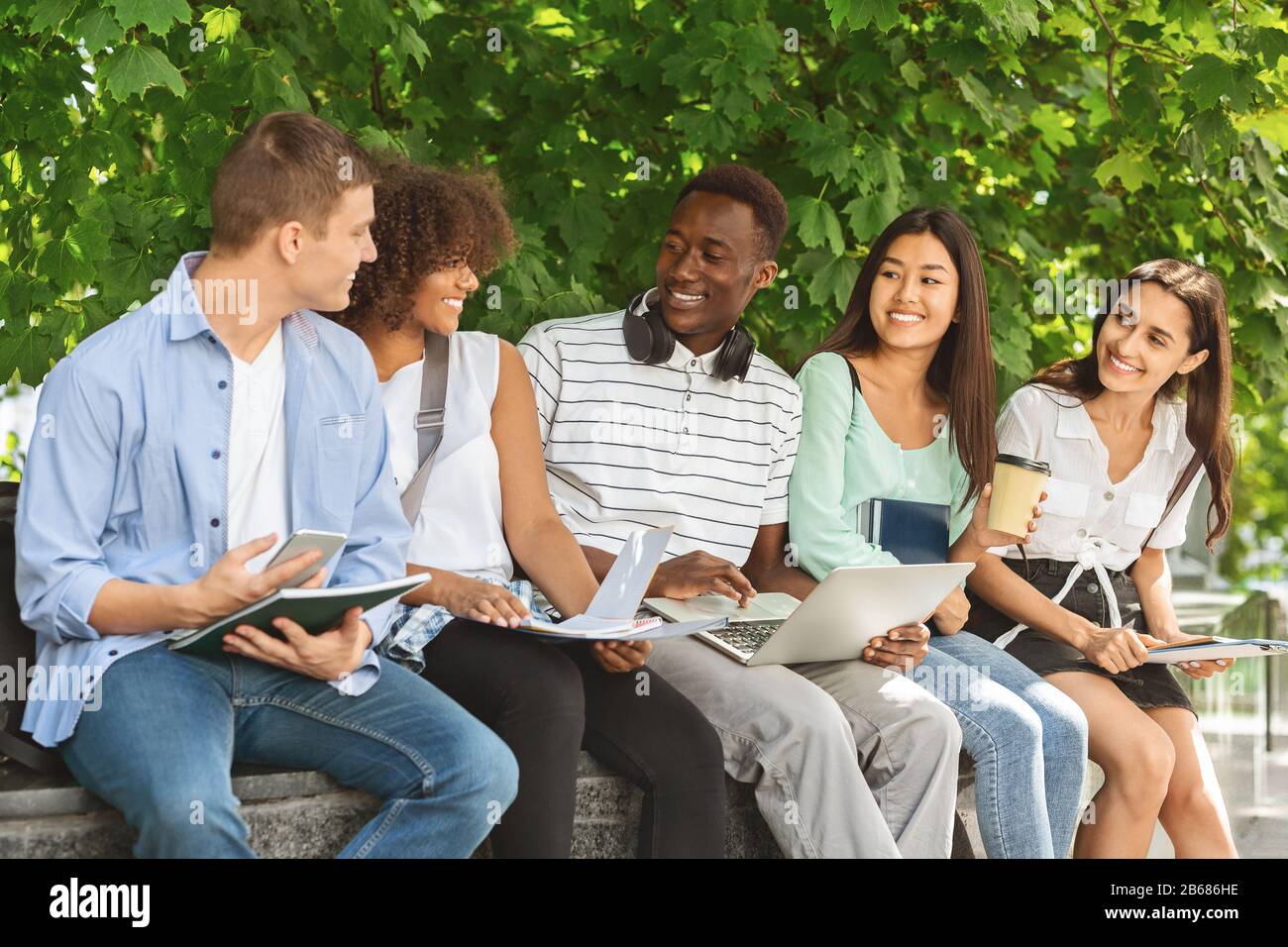 Group of multicultural students sitting in the university courtyard ...