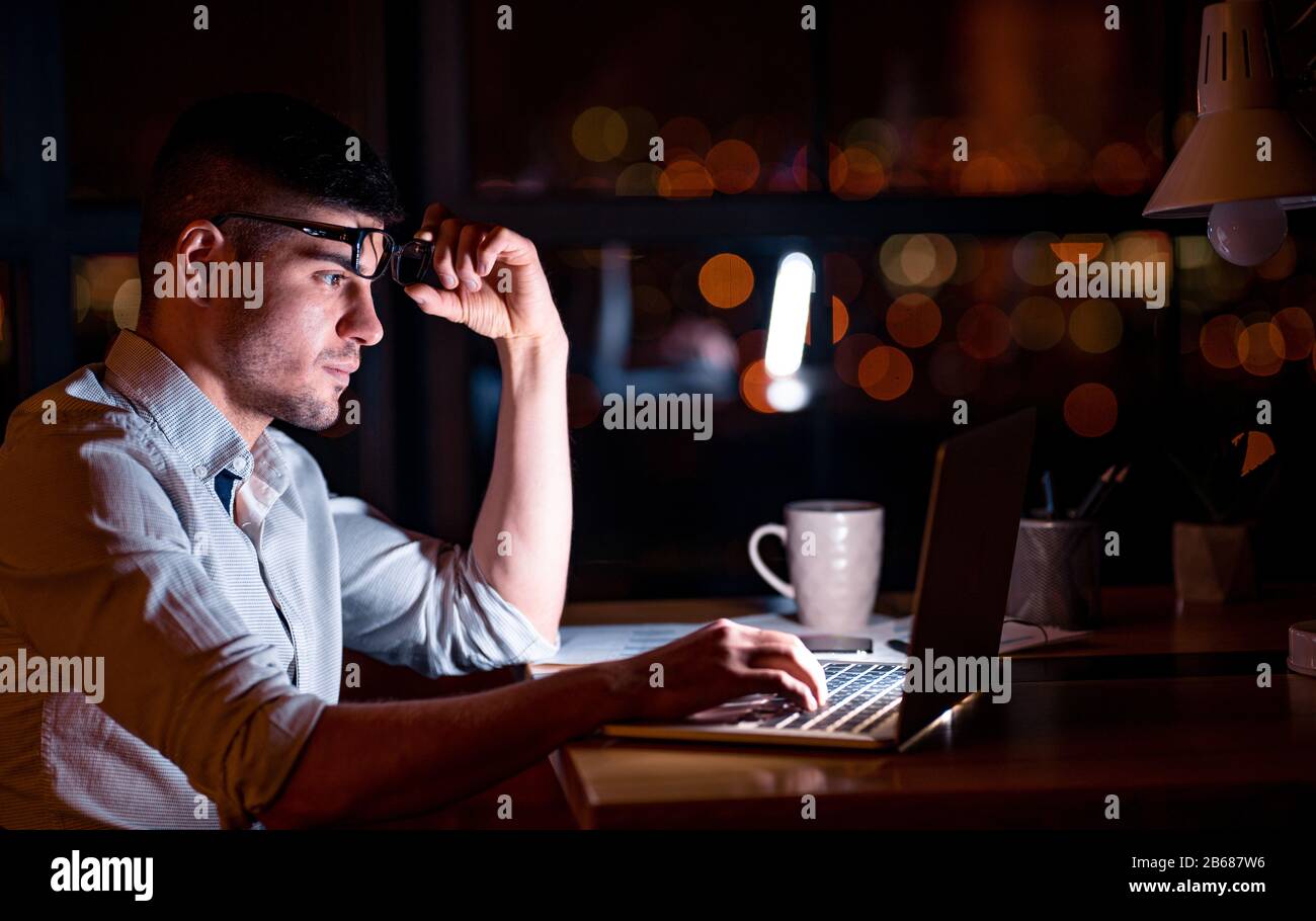 Office Manager Working On Laptop Overnight Sitting At Workplace Indoors ...