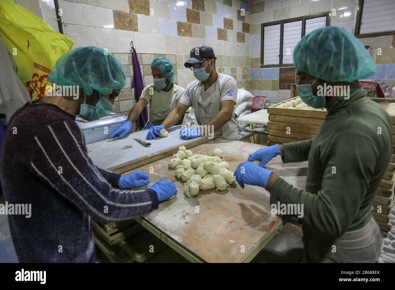 Palestinian workers wearing masks amid coronavirus precautions, bake ...