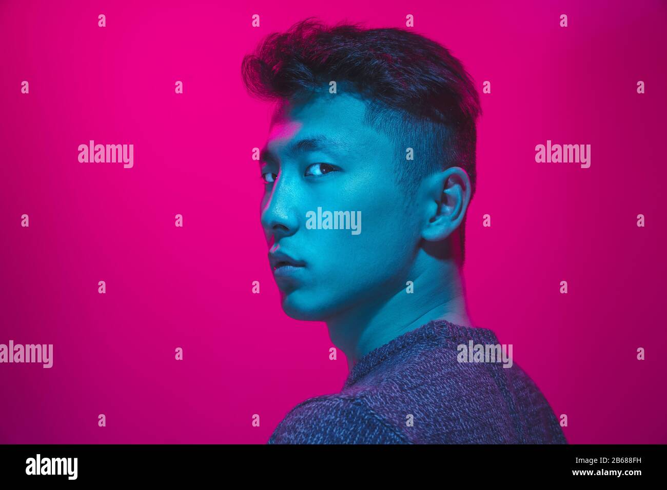 Portrait of a guy with colorful neon light on pink studio background ...