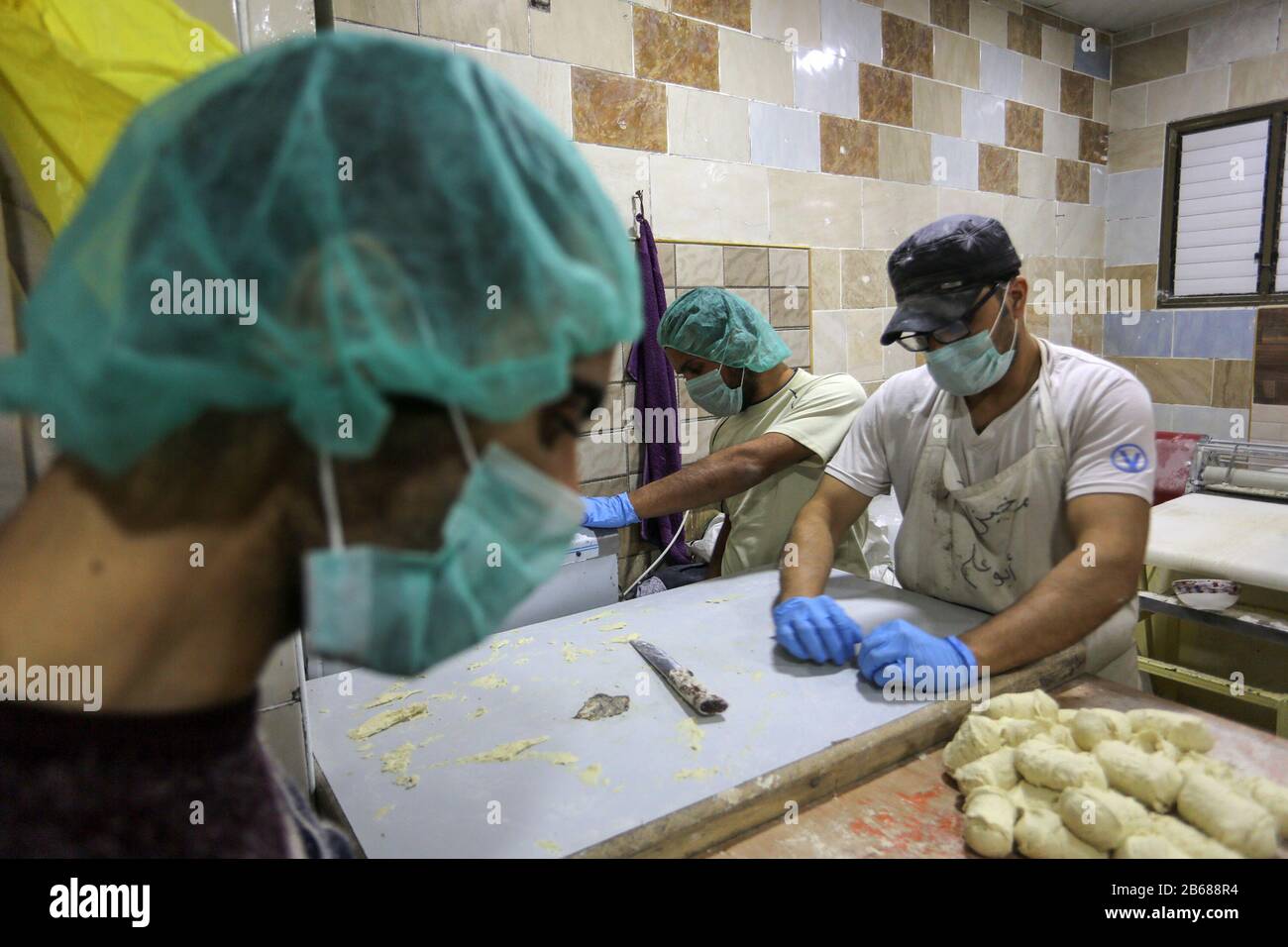 Palestinian workers wearing masks amid coronavirus precautions, bake ...