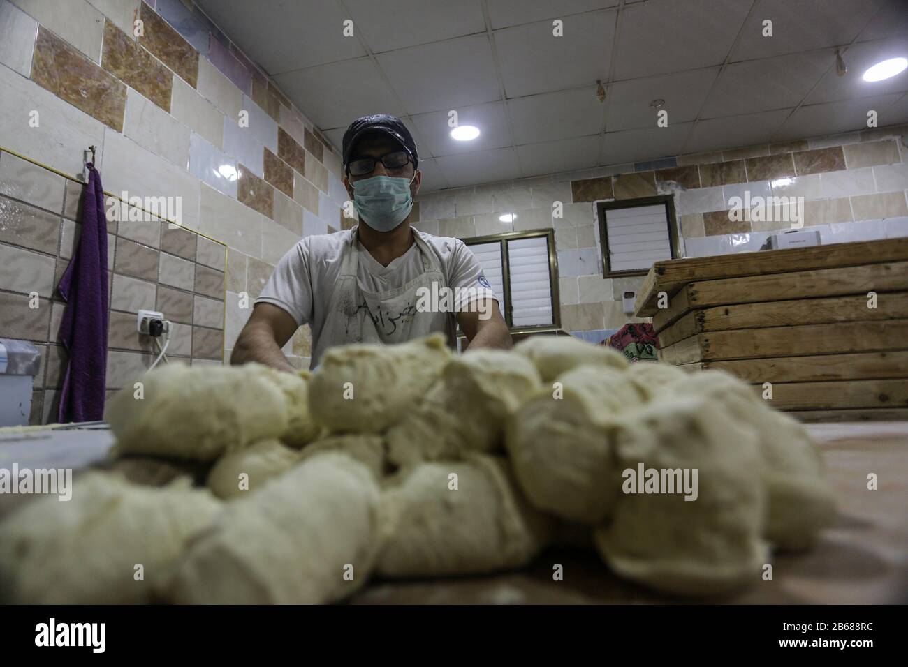 Palestinian workers wearing masks amid coronavirus precautions, bake ...