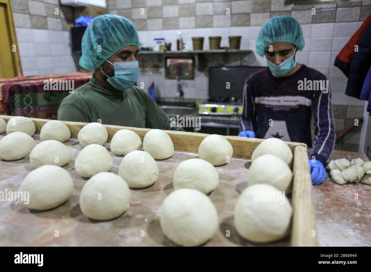 Palestinian workers wearing masks amid coronavirus precautions, bake ...