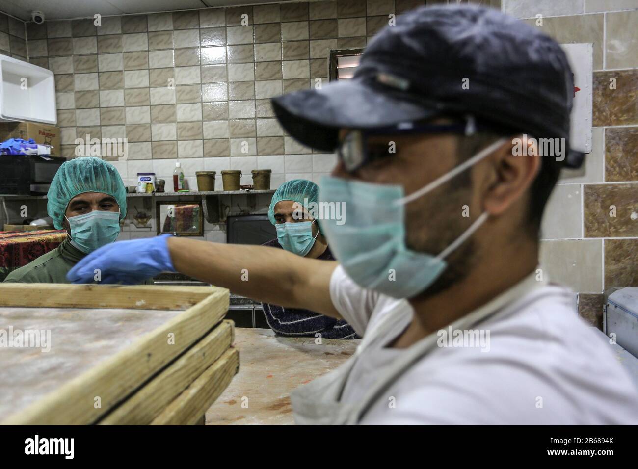 Palestinian workers wearing masks amid coronavirus precautions, bake ...