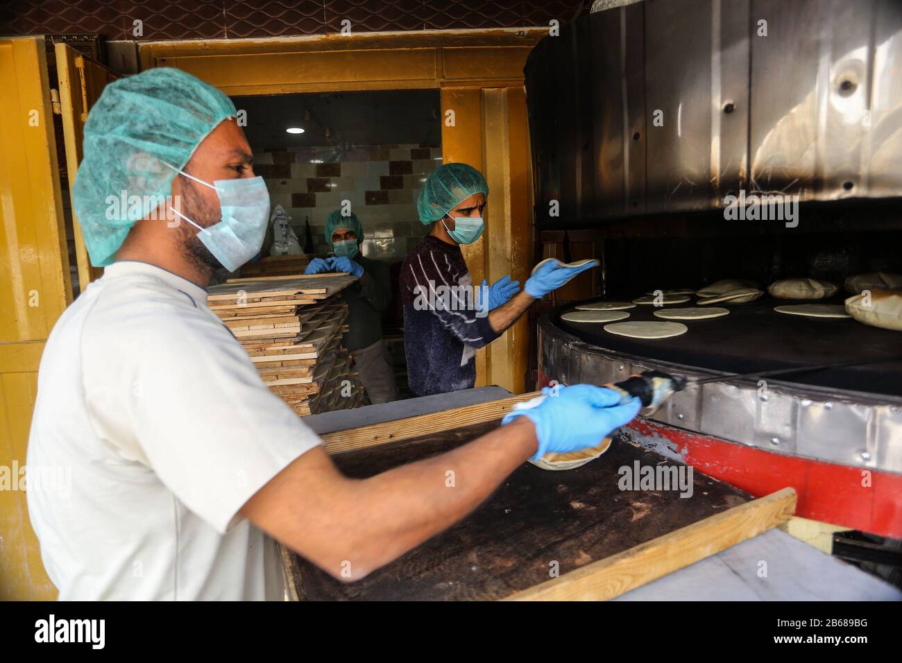 Palestinian workers wearing masks amid coronavirus precautions, bake ...