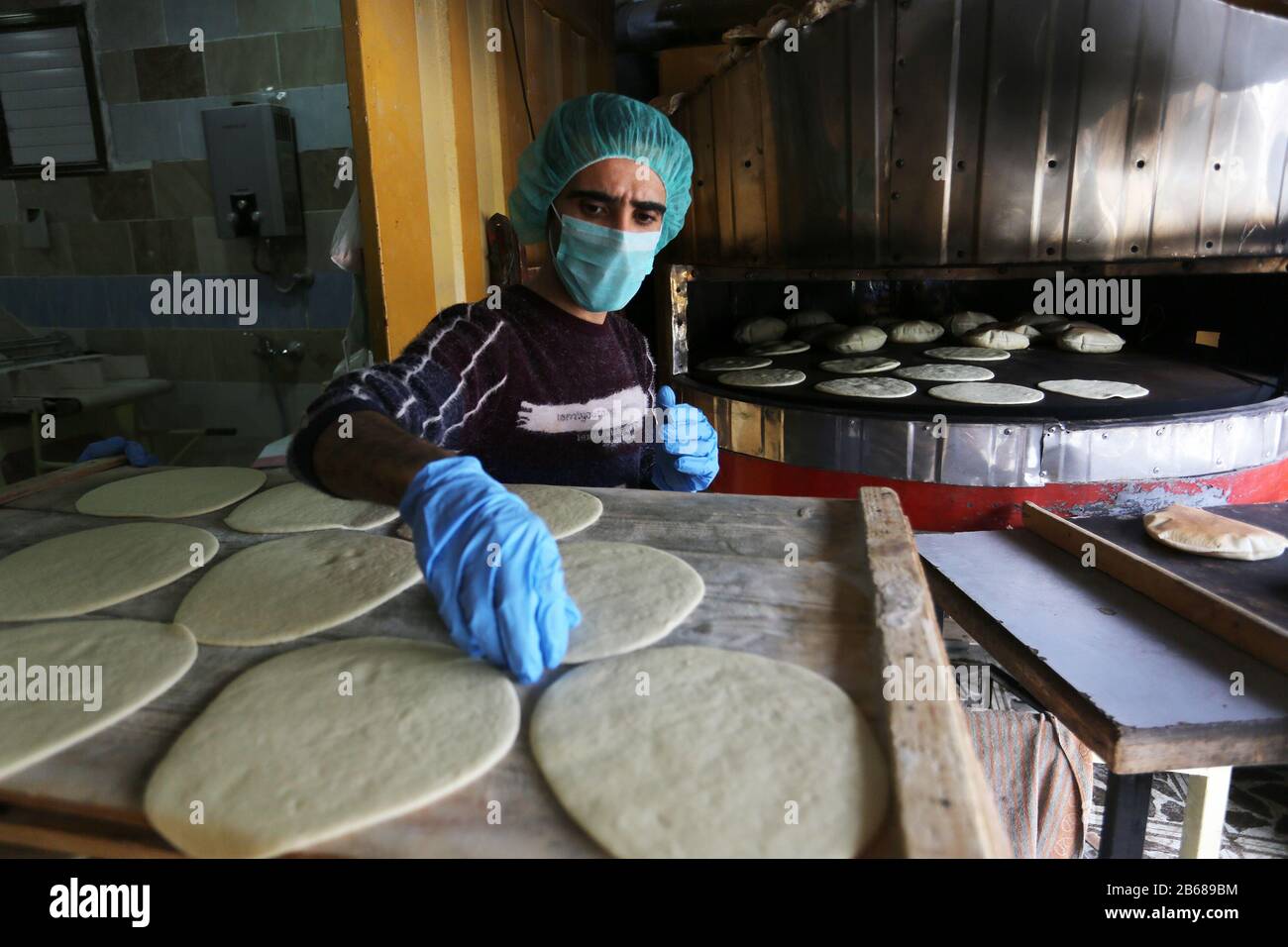 Palestinian workers wearing masks amid coronavirus precautions, bake ...