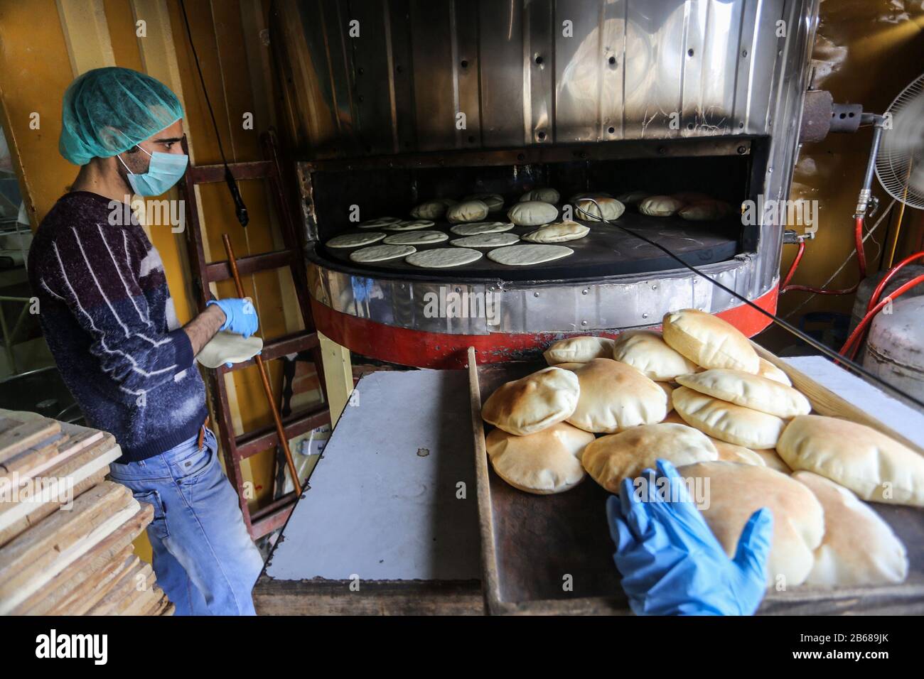 Palestinian workers wearing masks amid coronavirus precautions, bake ...