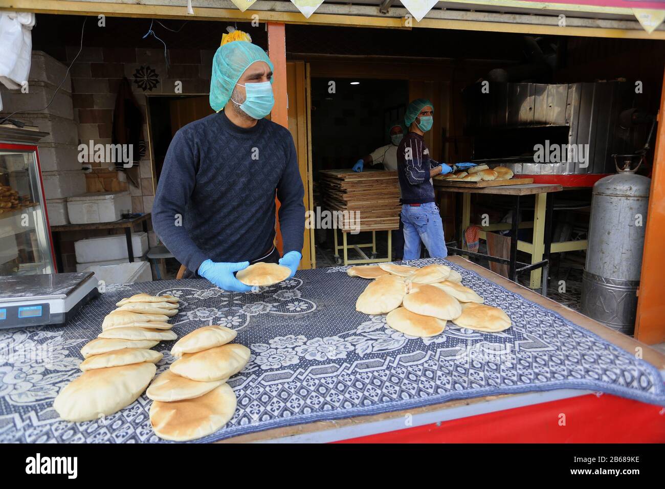 Palestinian workers wearing masks amid coronavirus precautions, bake ...