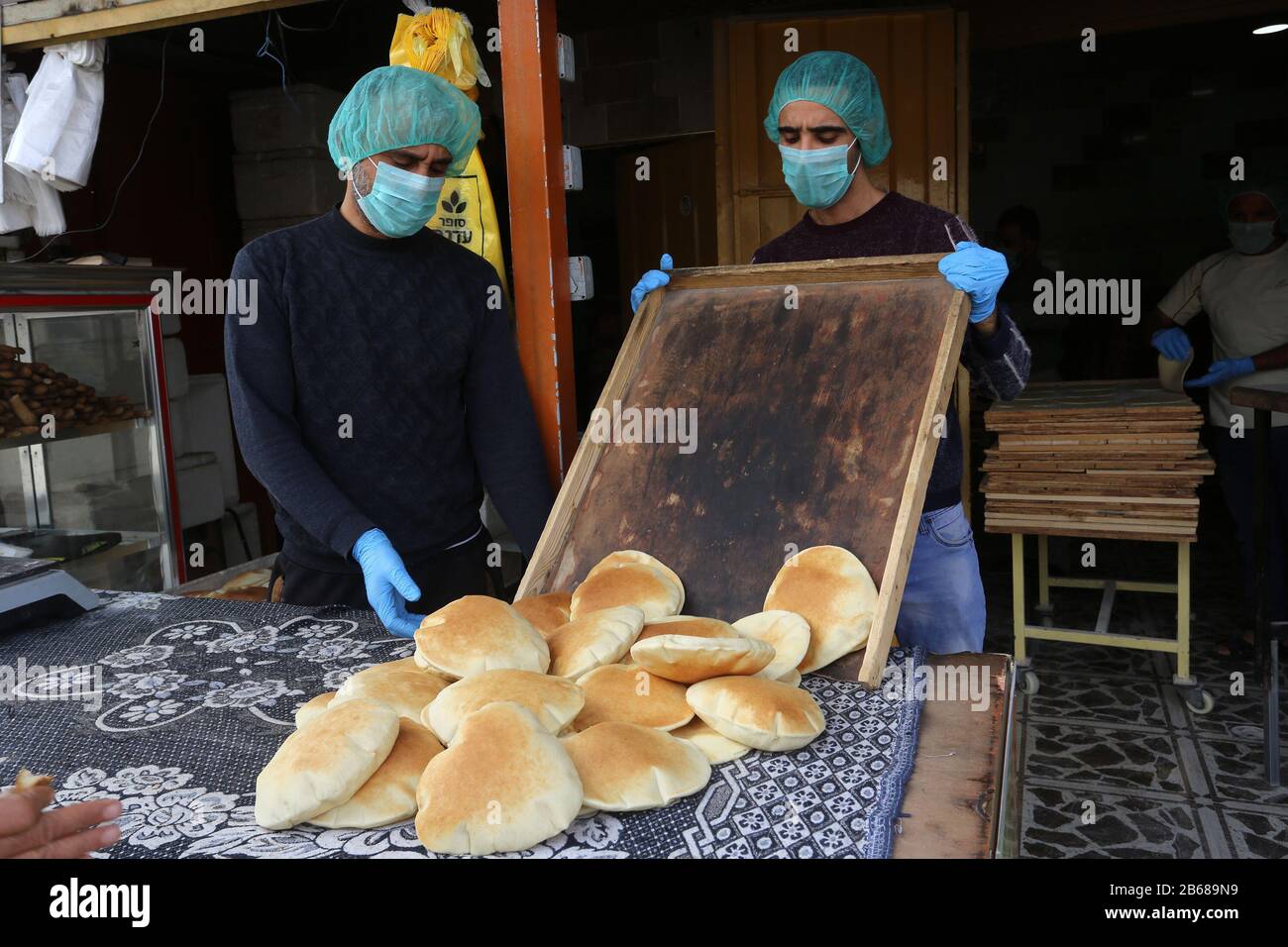 Palestinian workers wearing masks amid coronavirus precautions, bake ...
