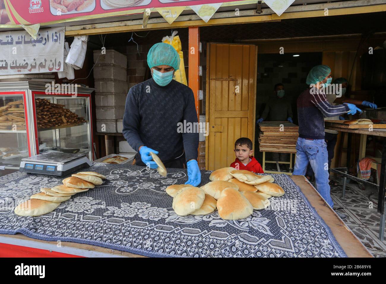 Palestinian workers wearing masks amid coronavirus precautions, bake ...