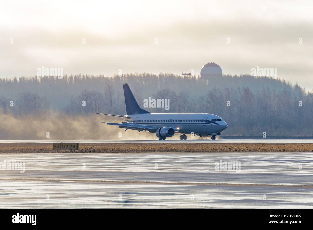 Aircraft after landing on runway with reverse turned on spray water ...