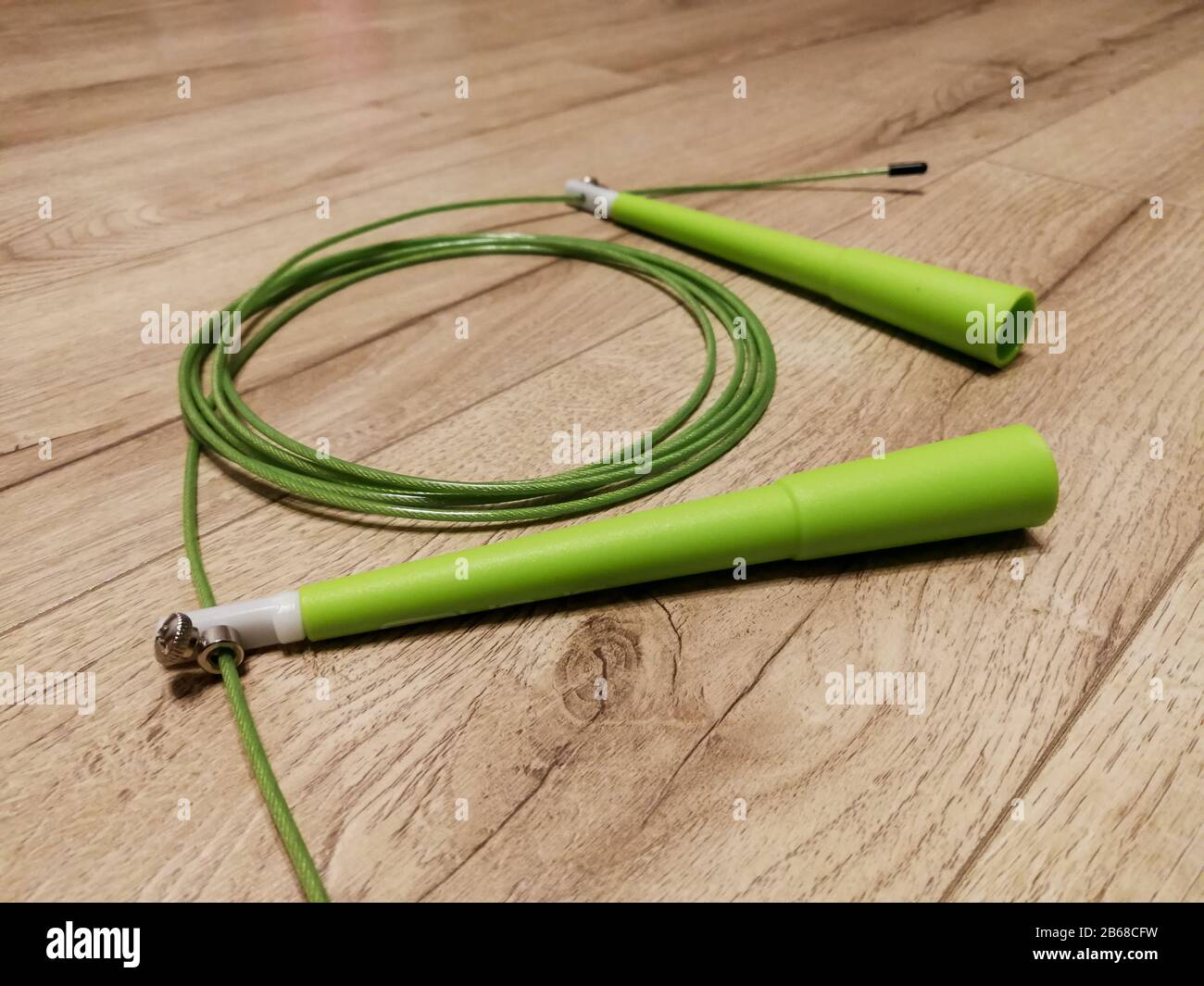 Professional jumping rope with green handles on the wooden background ...