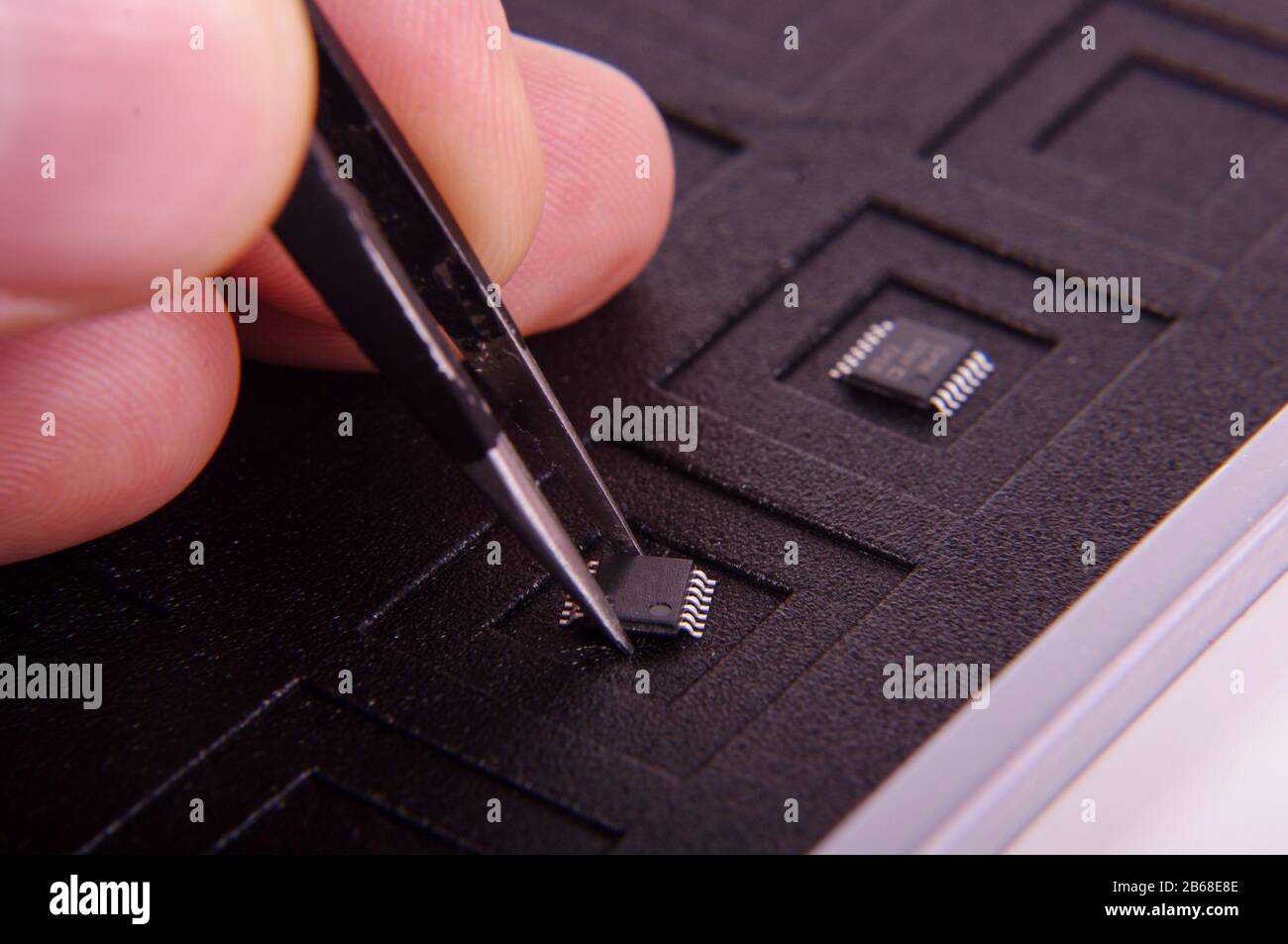 Tiny SMT technology electronics chip component and engineer holding it ...