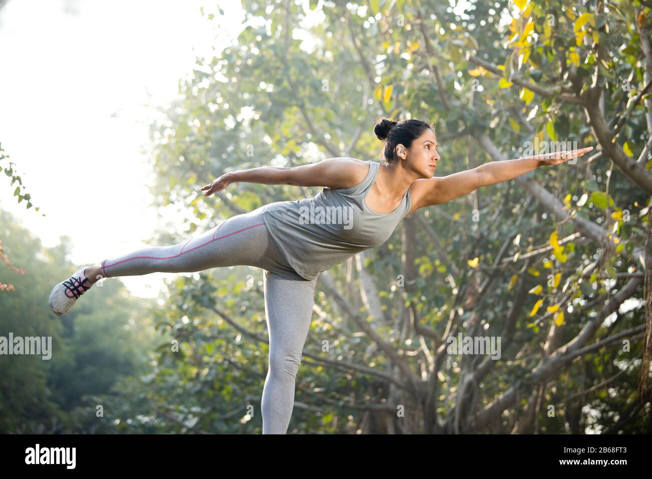 Woman standing on one leg and doing stretching exercise at park Stock ...