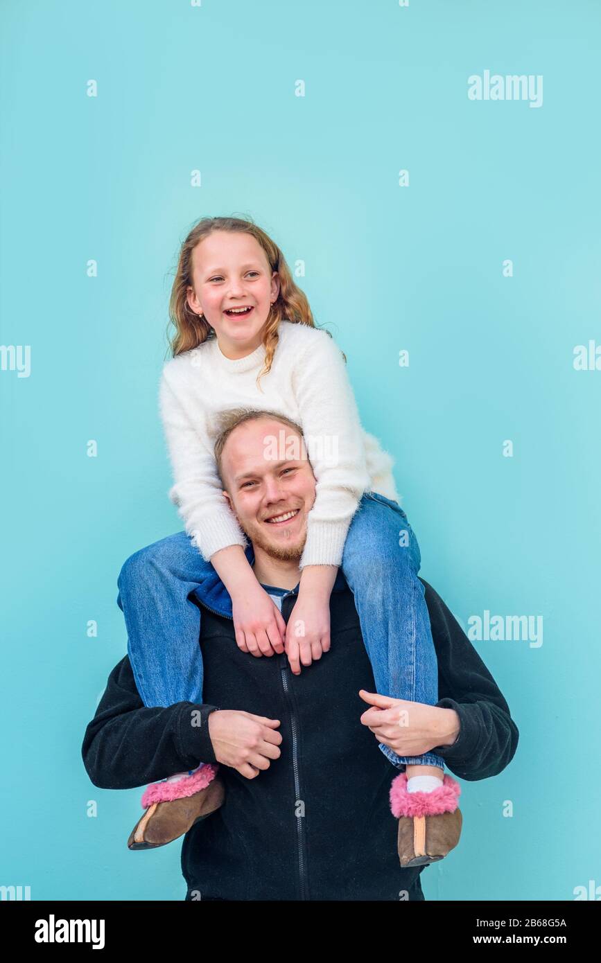 Brother giving piggyback ride to smiling sister on blue background ...