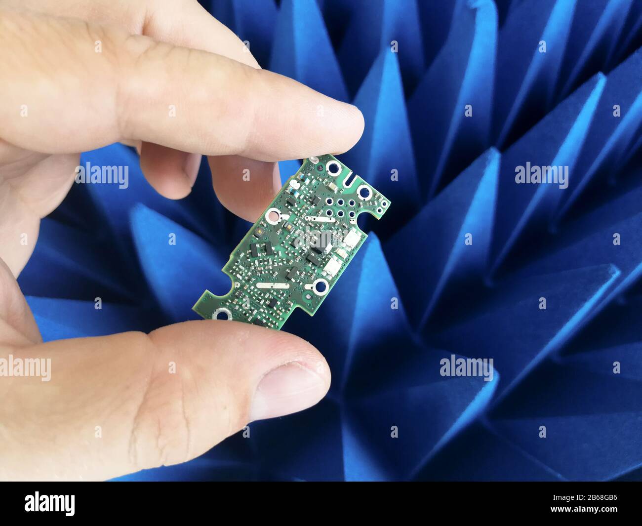 Electronics engineer hand holding printed circuit board in front of ...