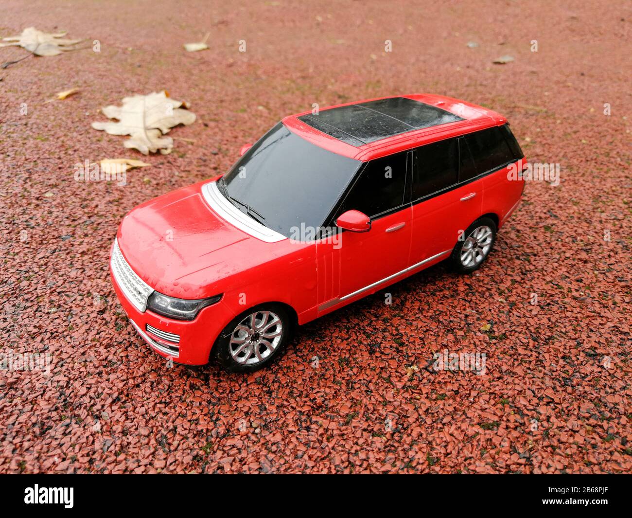 Red plastic radio controllable toy car on the red rubber playground ...