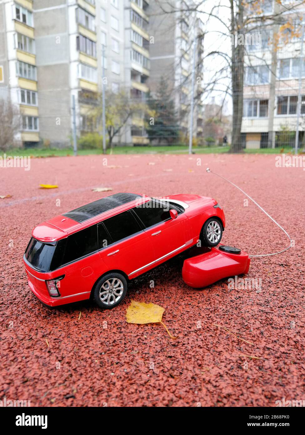 Red plastic radio controllable toy car on the red rubber playground ...
