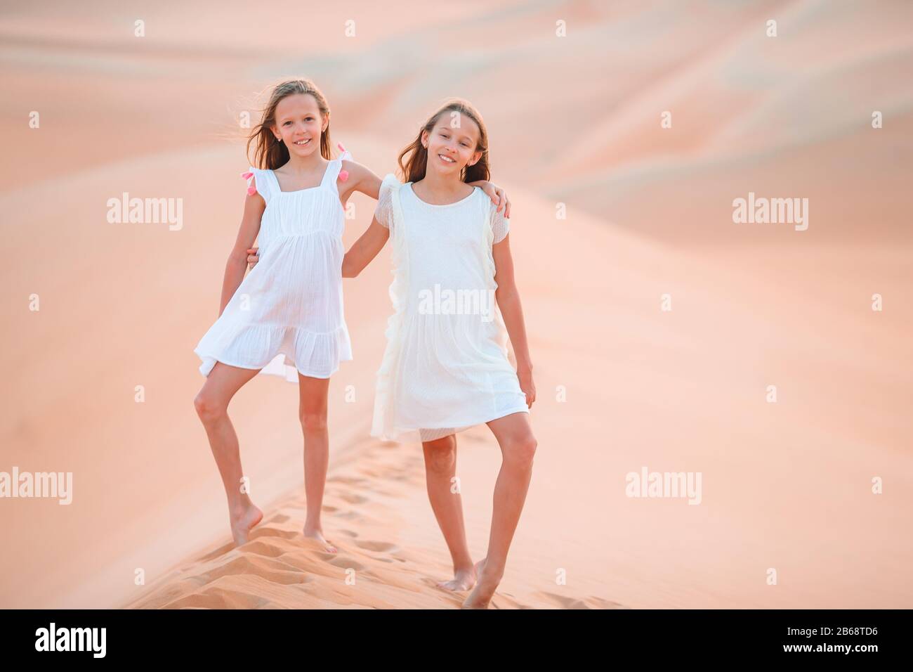 Girls among dunes in big desert in Emirates Stock Photo - Alamy
