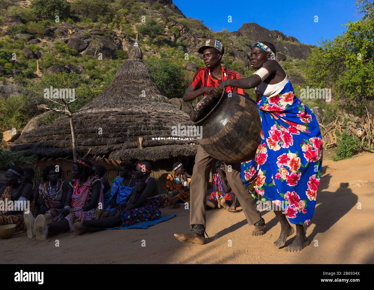 Larim tribe people carrying alcohol in a jar during a wedding ceremony ...