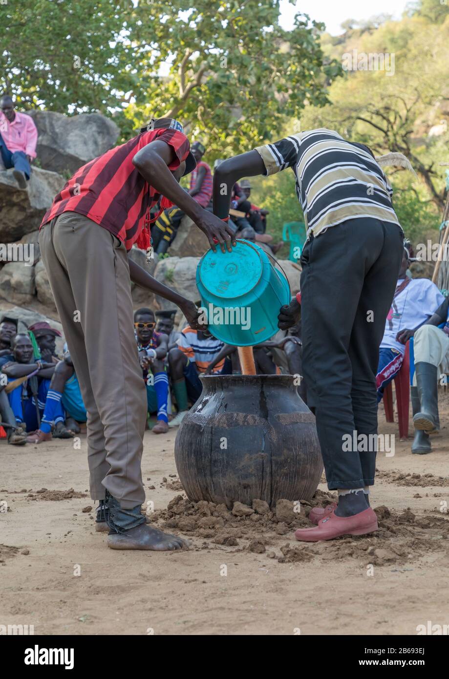 Larim tribe men putting alcohol in a jar during a wedding ceremony ...