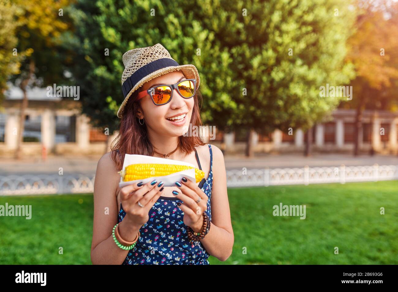 Woman eating street food corn in summer park, travel food concept Stock ...