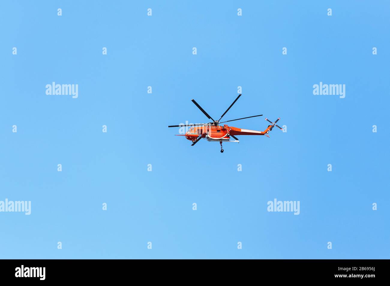 Red firefighter Helicopter flying fast in the blue sky during the ...