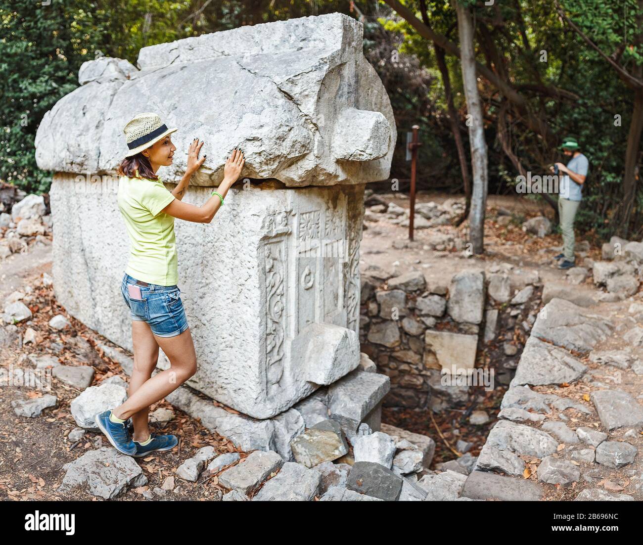 A woman archaeologist or tourist touches an ancient sarcophagus in the ...