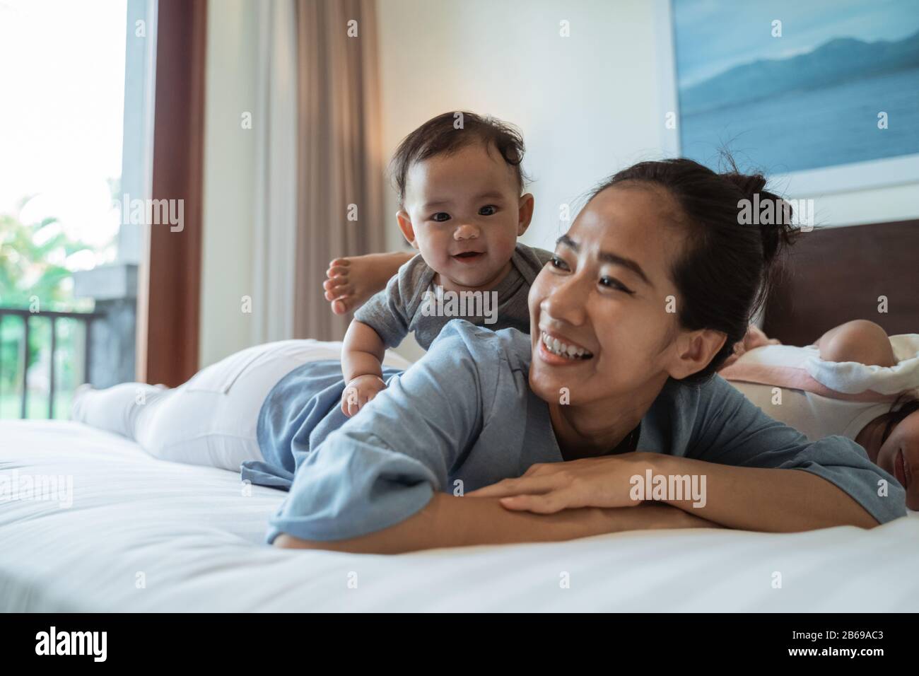 Mother Lying In Bed With Her Daughter While Playing In The Bedroom