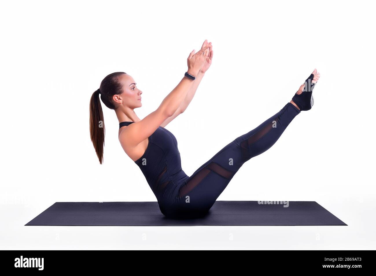 Girl on a white background does a teaser exercise. Yoga. Pilates ...