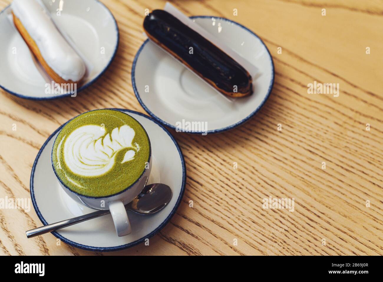 Green matcha with a eclair. Cozy coffee shop Stock Photo - Alamy