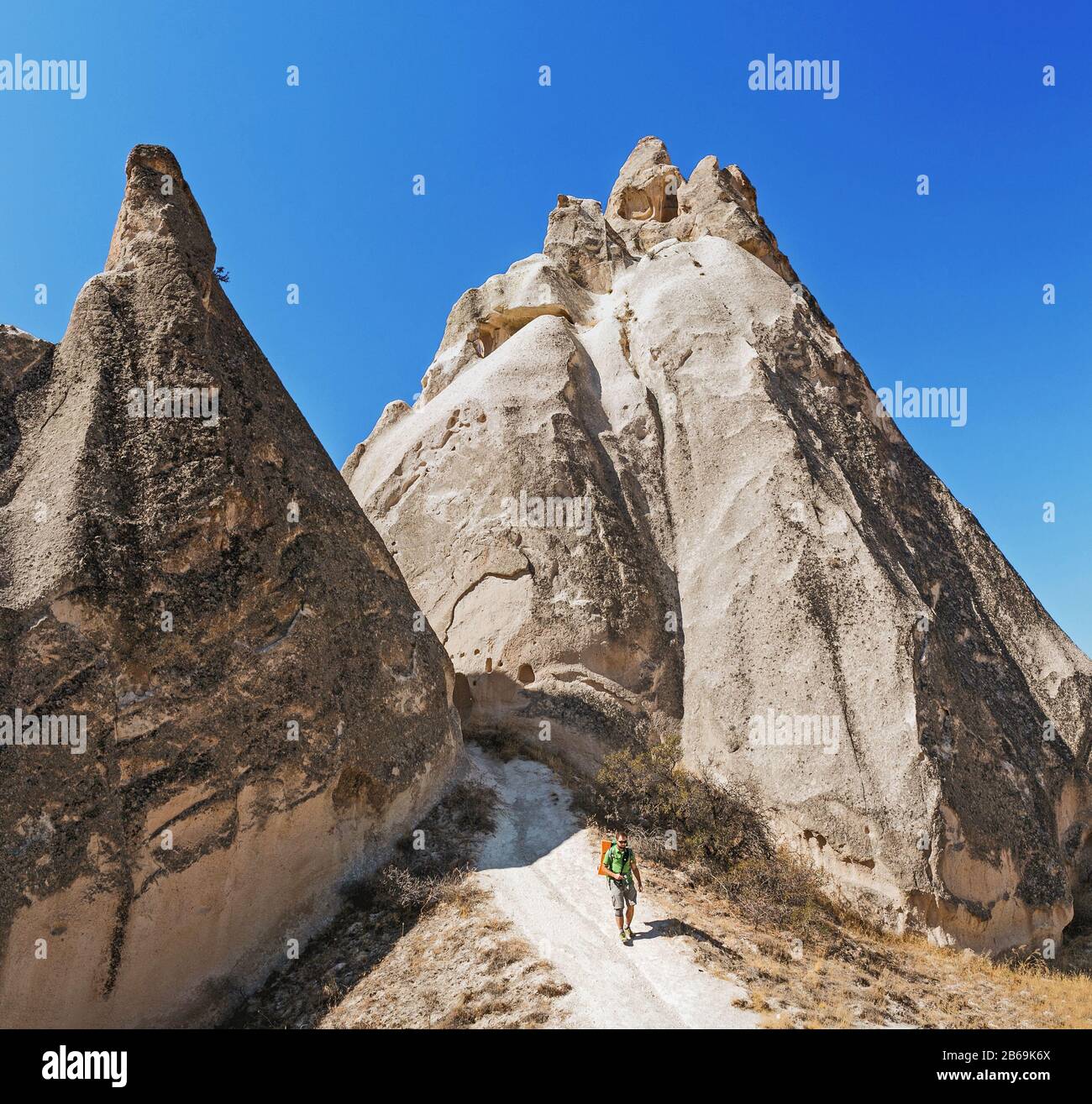 Tourist walking by path among caves and tuff rocks in Cappadocia, a ...