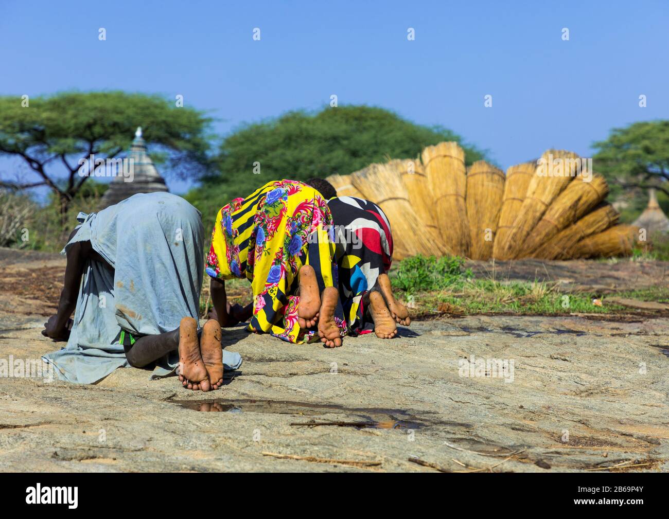 Larim tribe girls grinding sorghum grains in holes in a rock, Boya ...