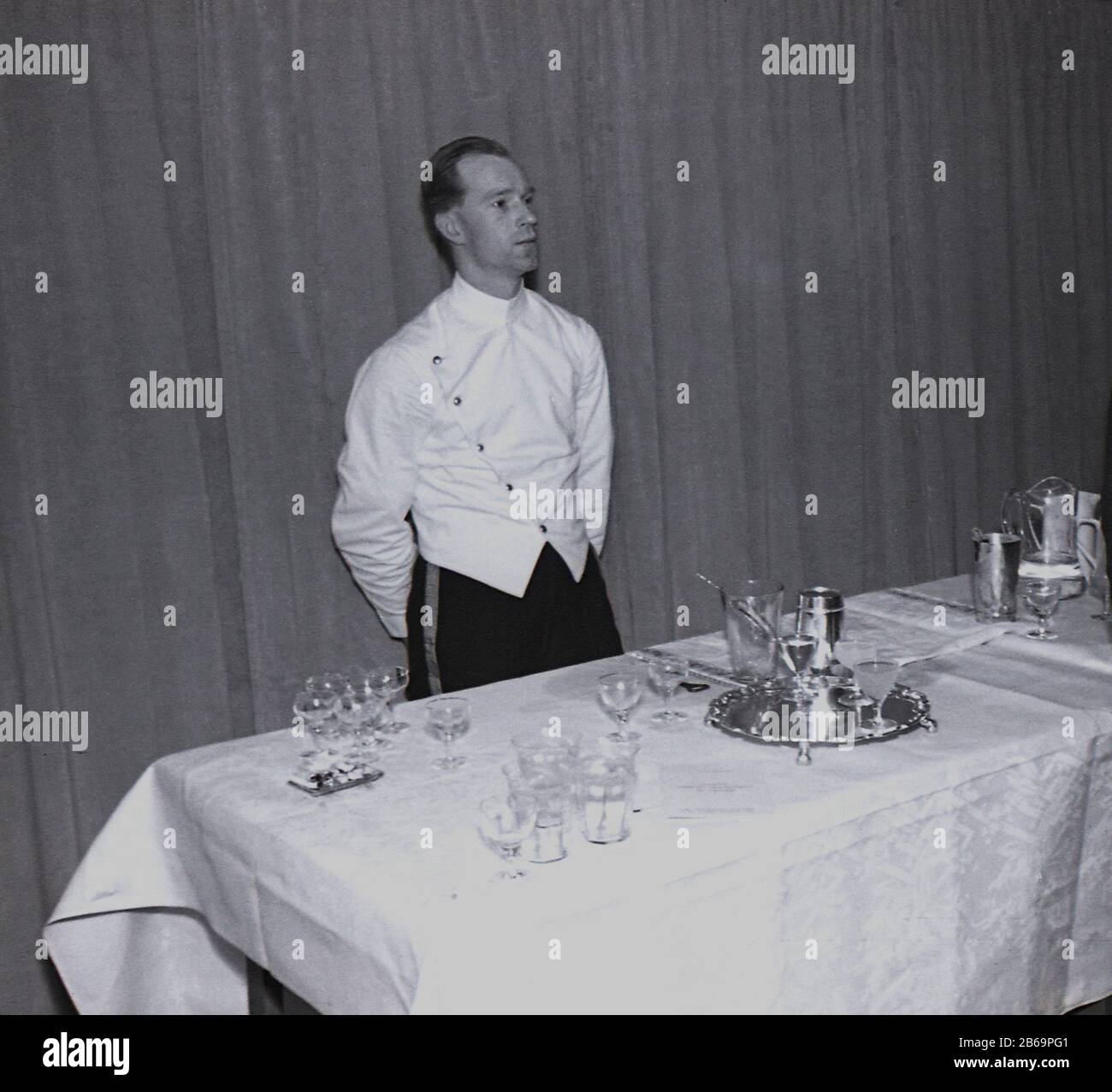 1950s, historical, a uniformed waiter standing by ready to serve drinks ...