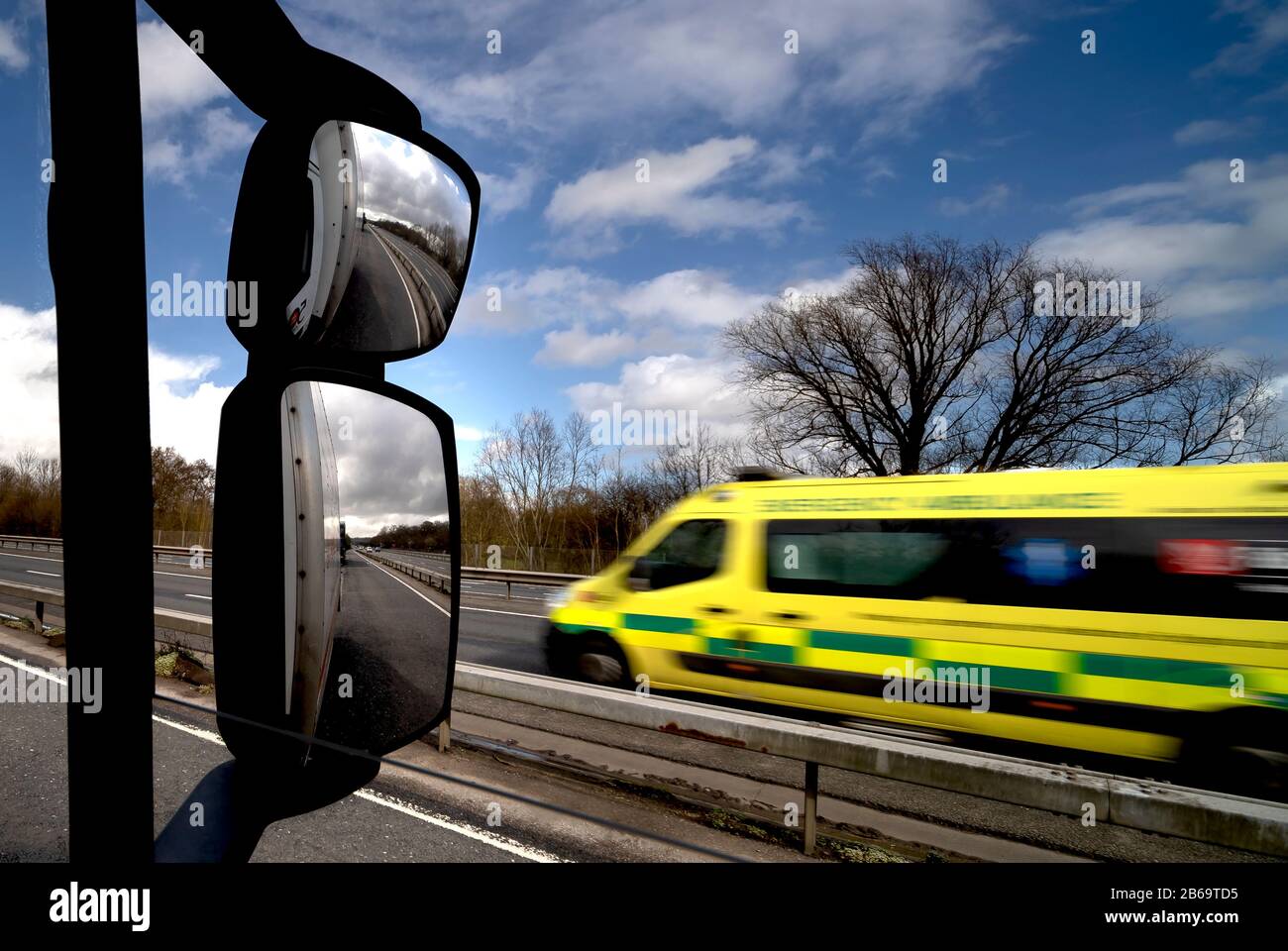 Lorry side mirror view, with blurred ambulance Stock Photo - Alamy