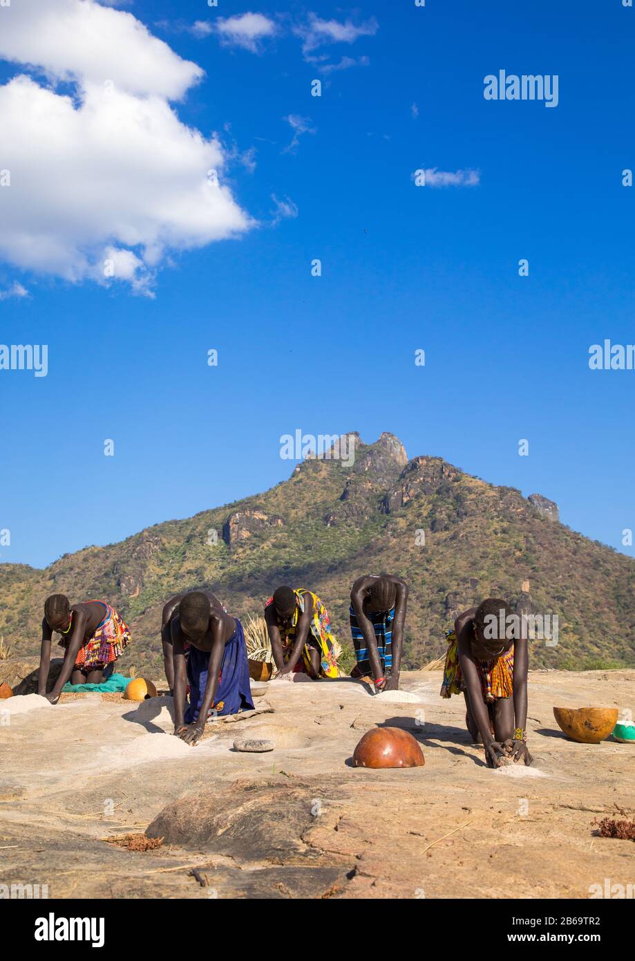 Larim tribe women grinding sorghum grains in holes in a rock, Boya ...