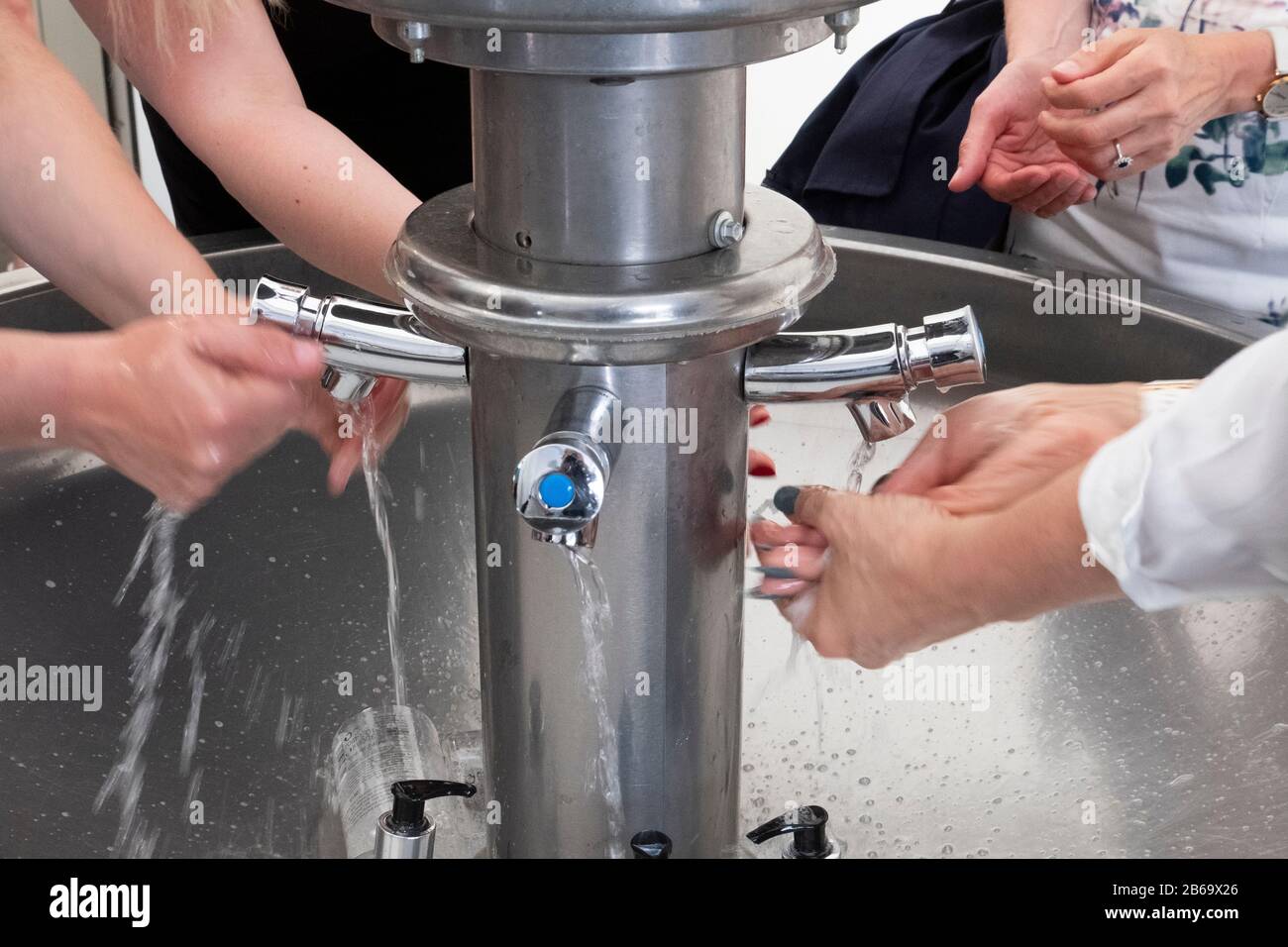 4 people hand washing at a communal wash stand Stock Photo - Alamy
