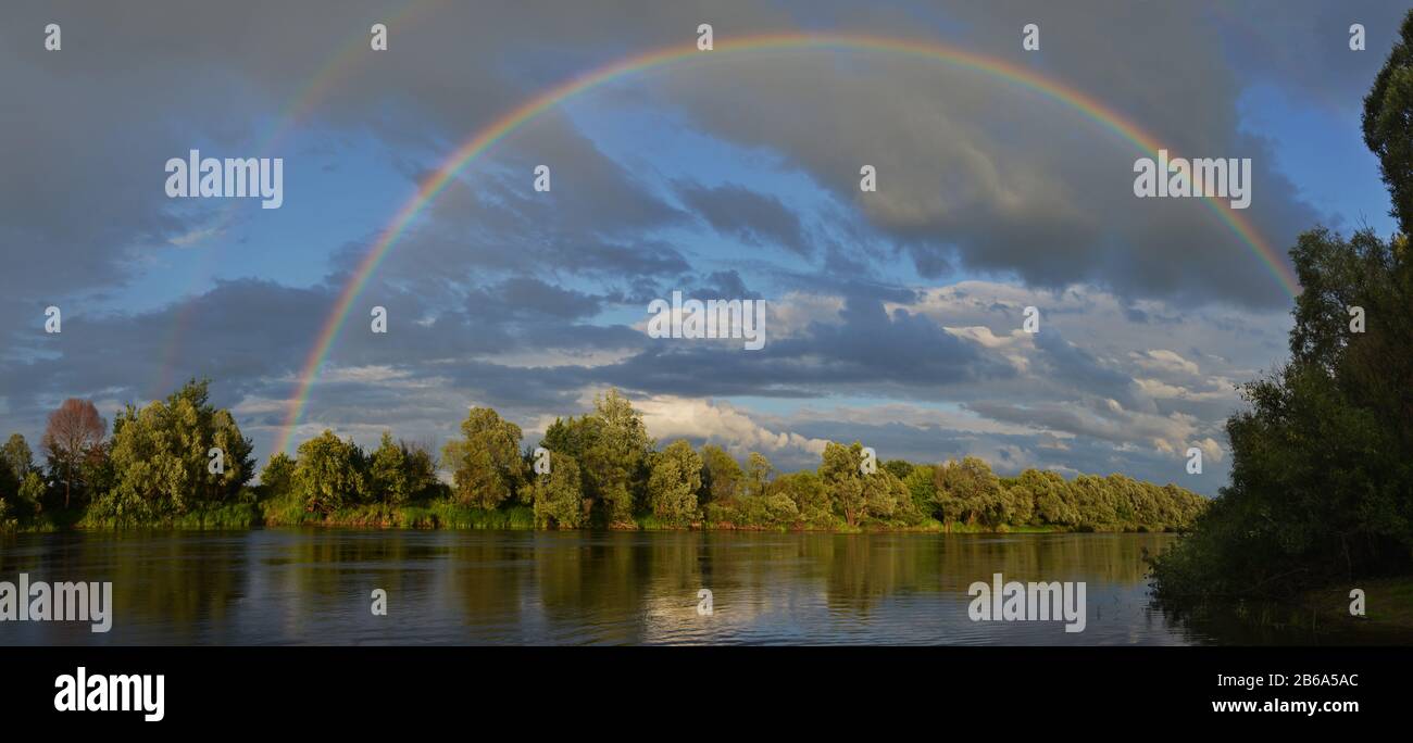 Two rainbow over the river. Beautiful sky with dark clouds in ...