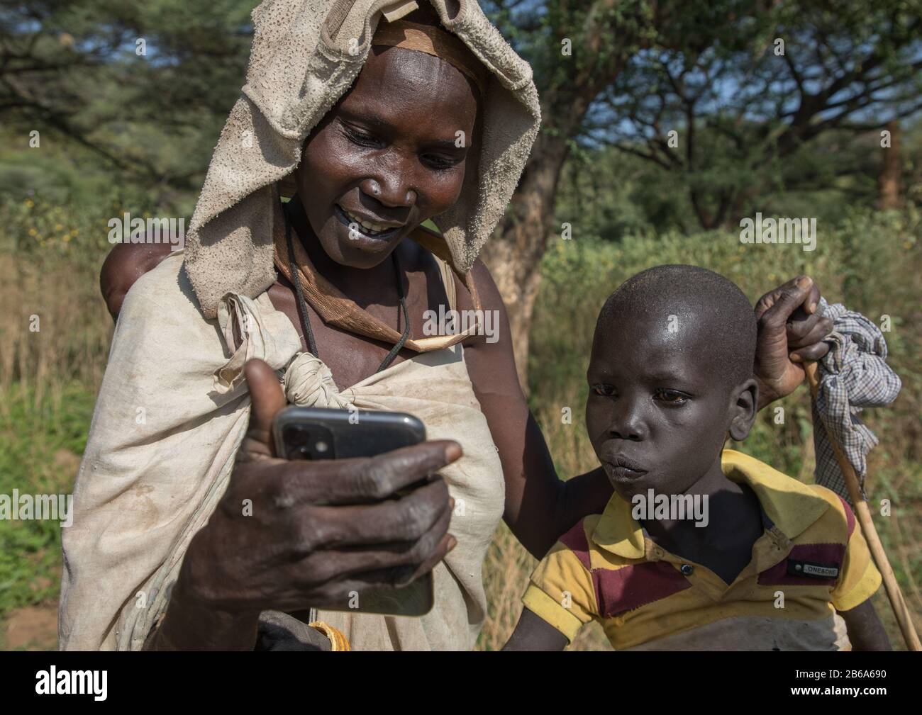 Mourning Larim tribe woman showing a mobile phone to her son, Boya ...
