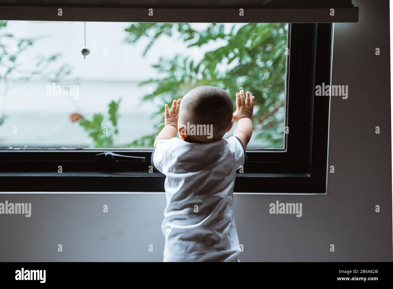 little baby holding the window glass and looking out of window Stock ...