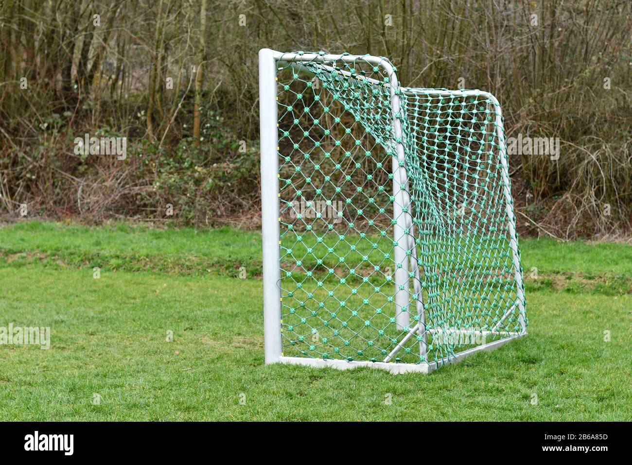 Side view of empty soccer goal with white frame and green net standing ...