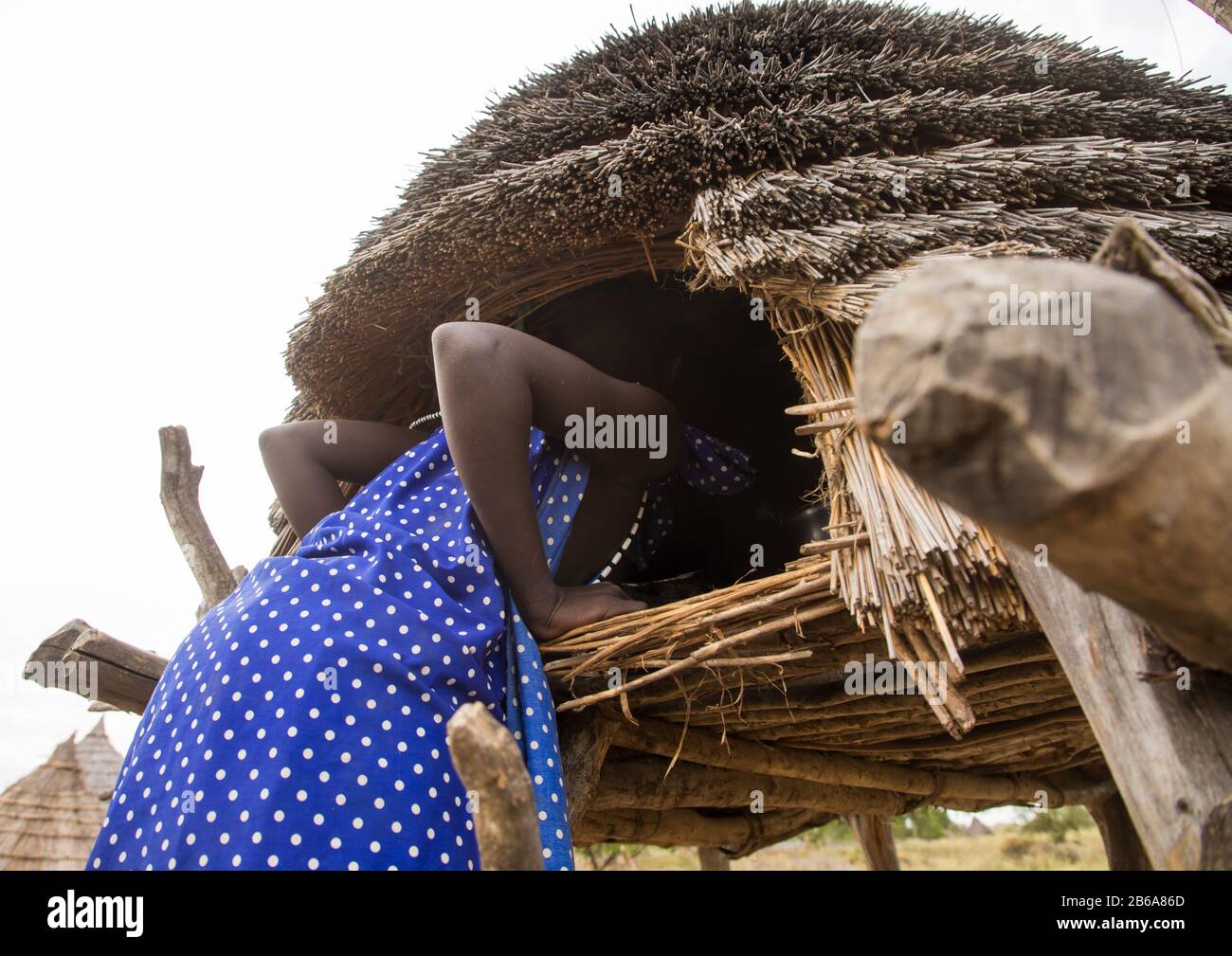 Toposa tribe girl climbing in a granary in a village, Namorunyang State ...