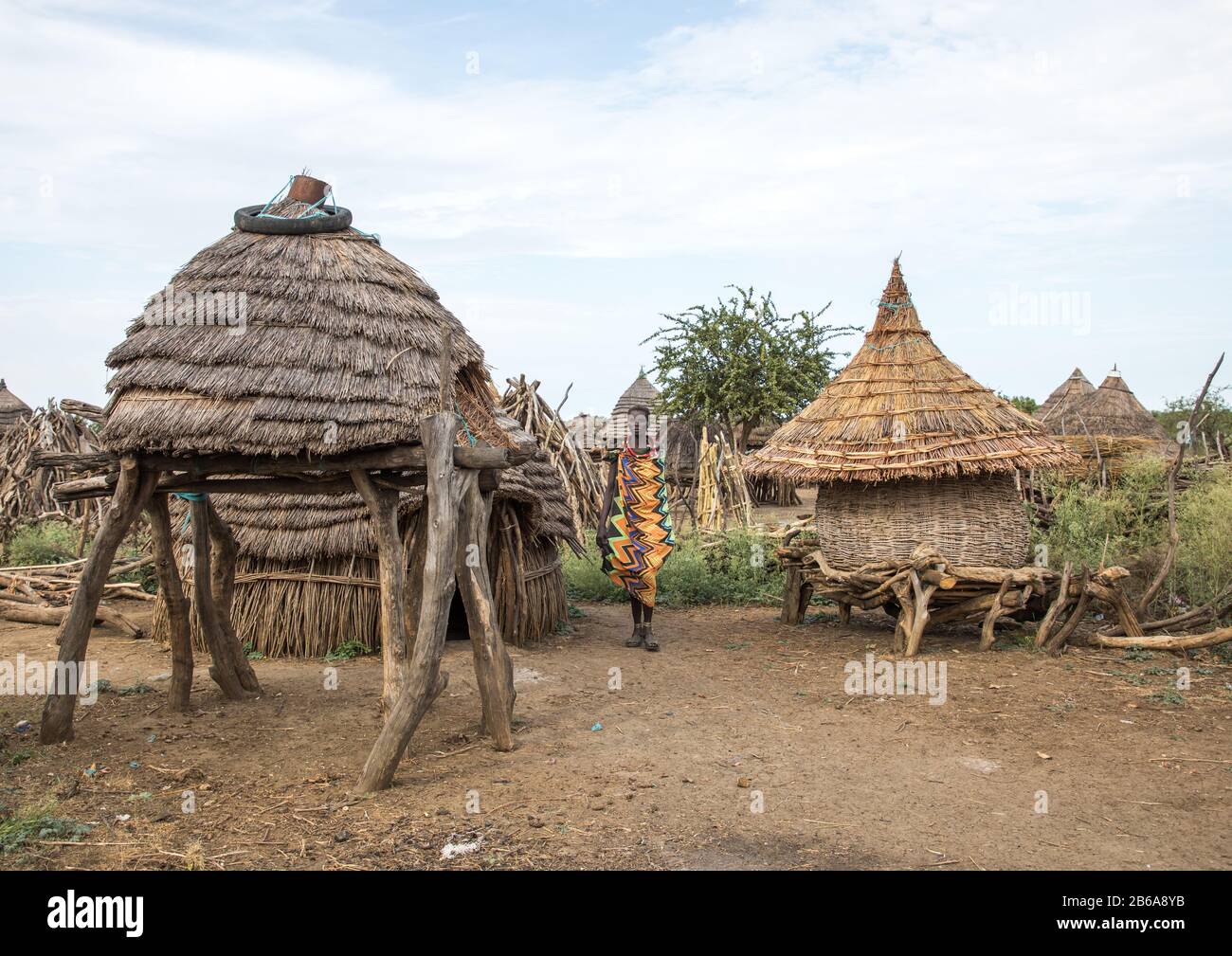 Toposa tribe woman passing near granaries in a village, Namorunyang ...