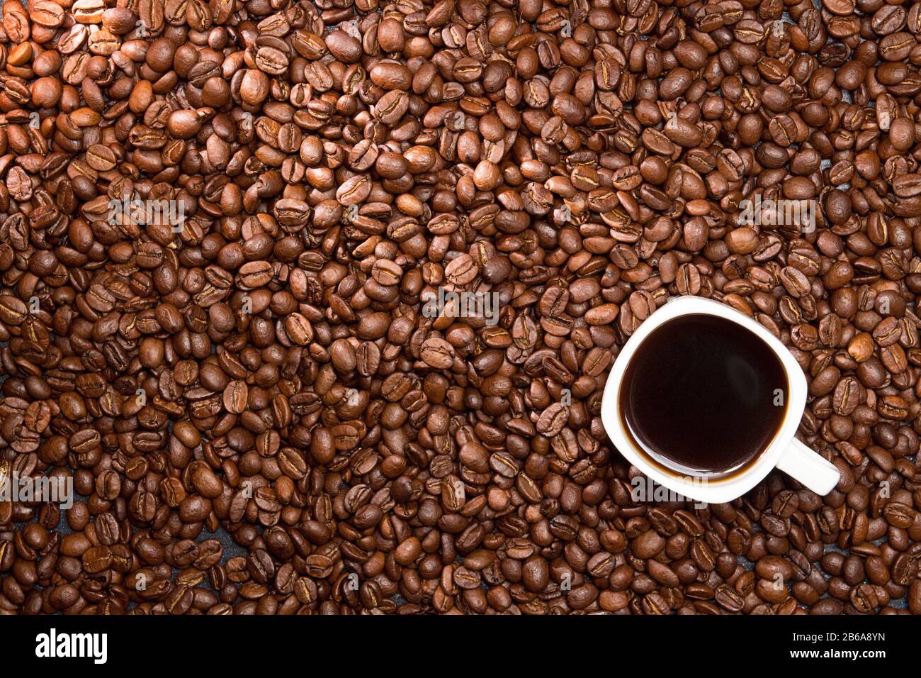 Coffee background. Heap coffee beans and cup of coffee over on table ...