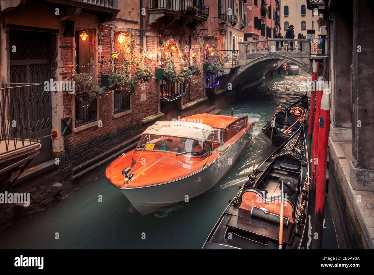 A famous Venetian water taxi travels down a narrow canal in Venice ...