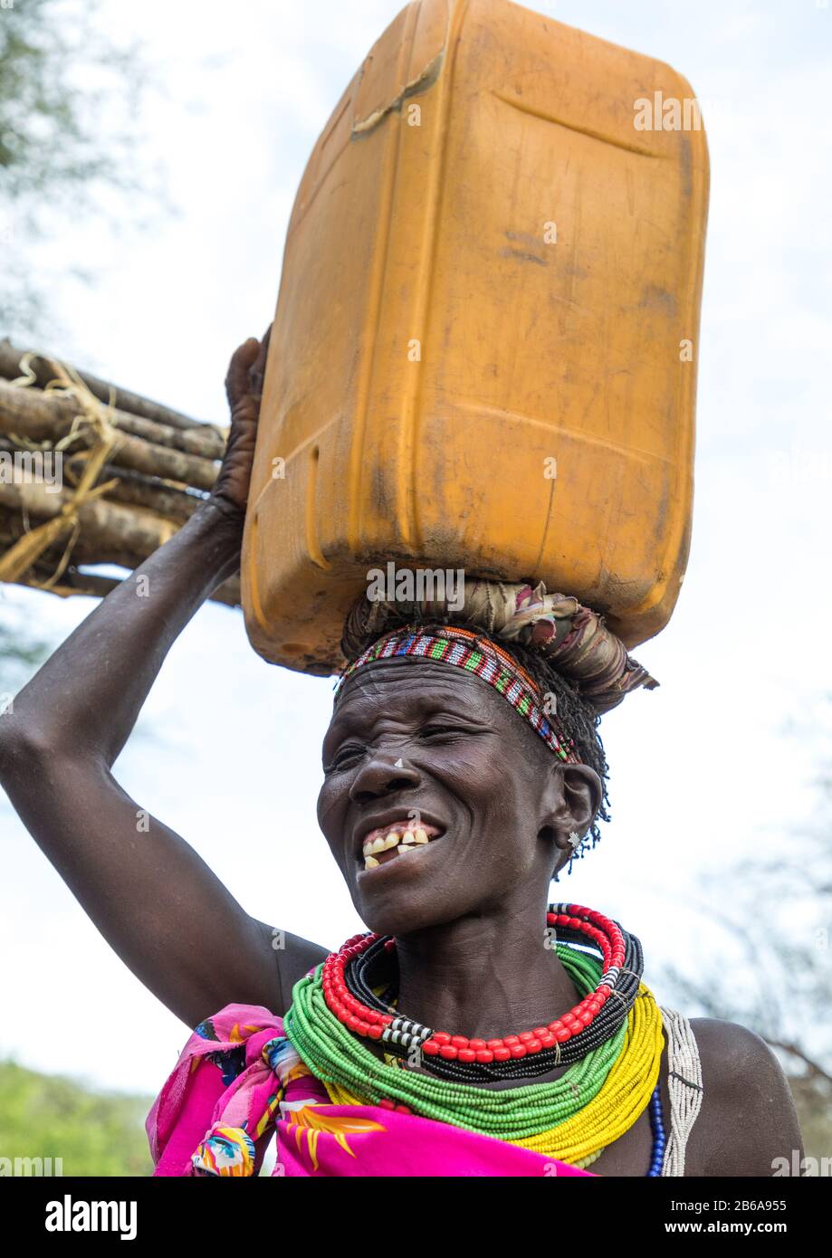 Smiling Toposa tribe woman carrying a jerrycan on her head, Namorunyang ...