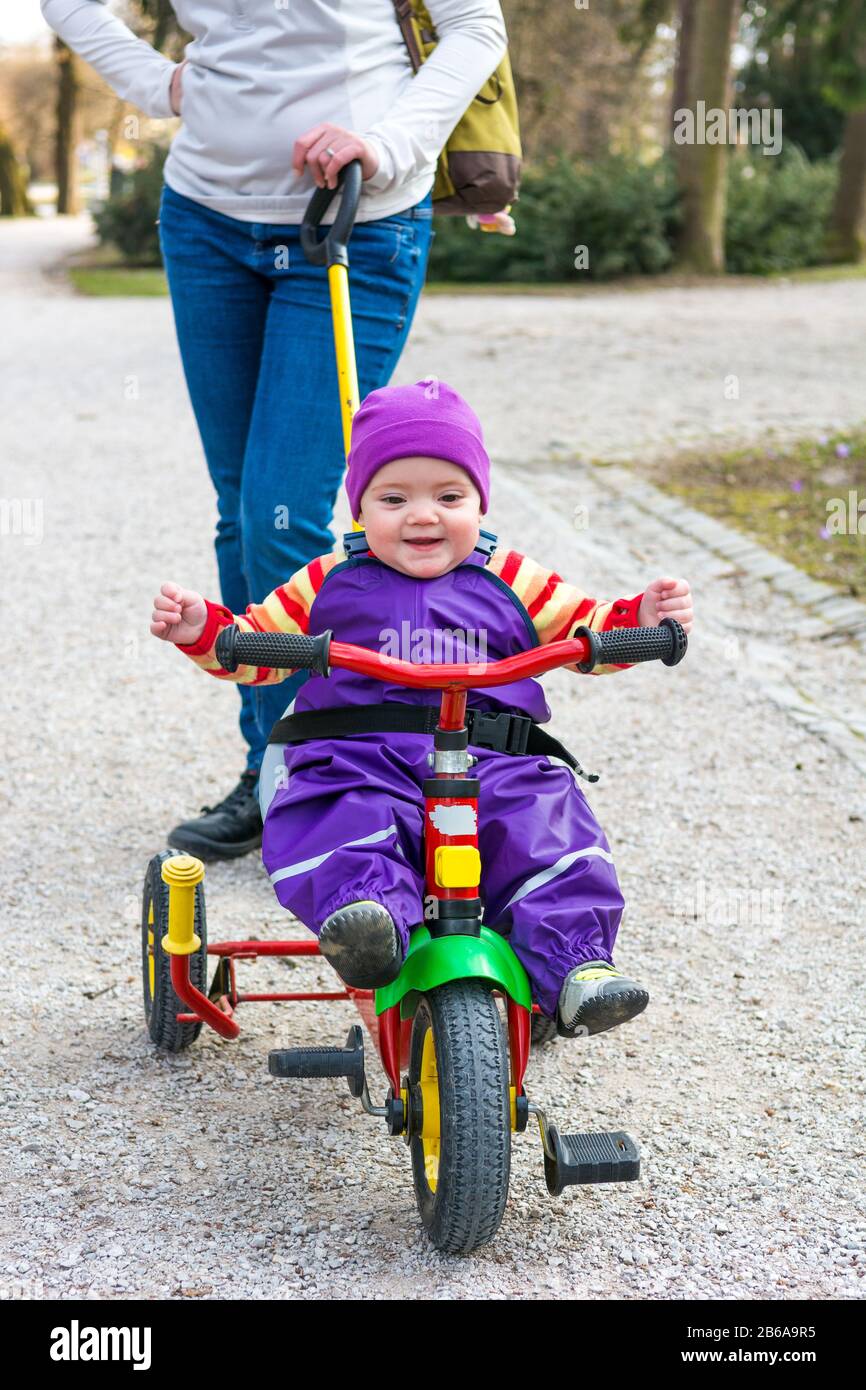 Cute baby girl enjoying her first bycicle ride with mothers help Stock ...