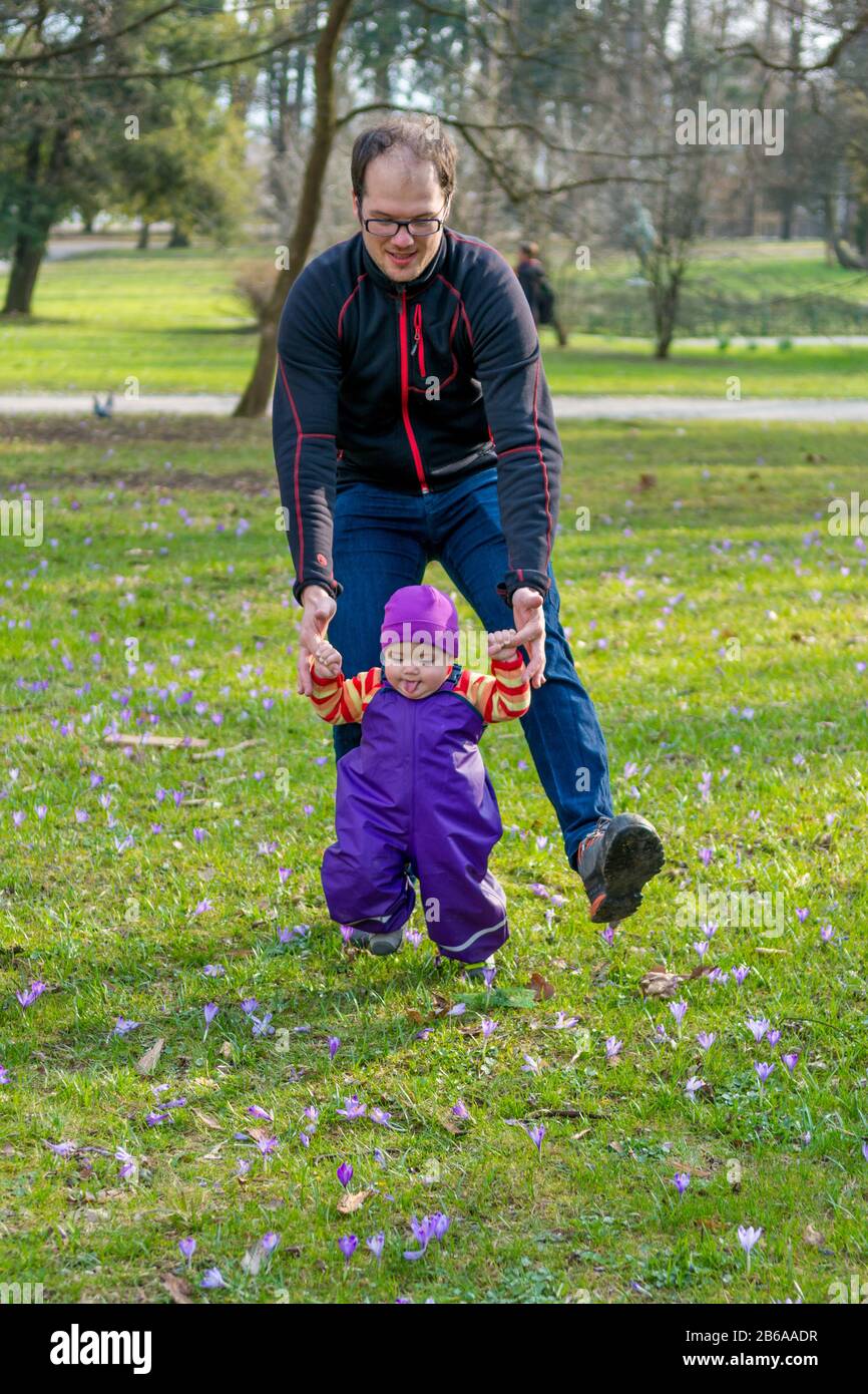 Baby girl making her first steps with support of her father Stock Photo ...