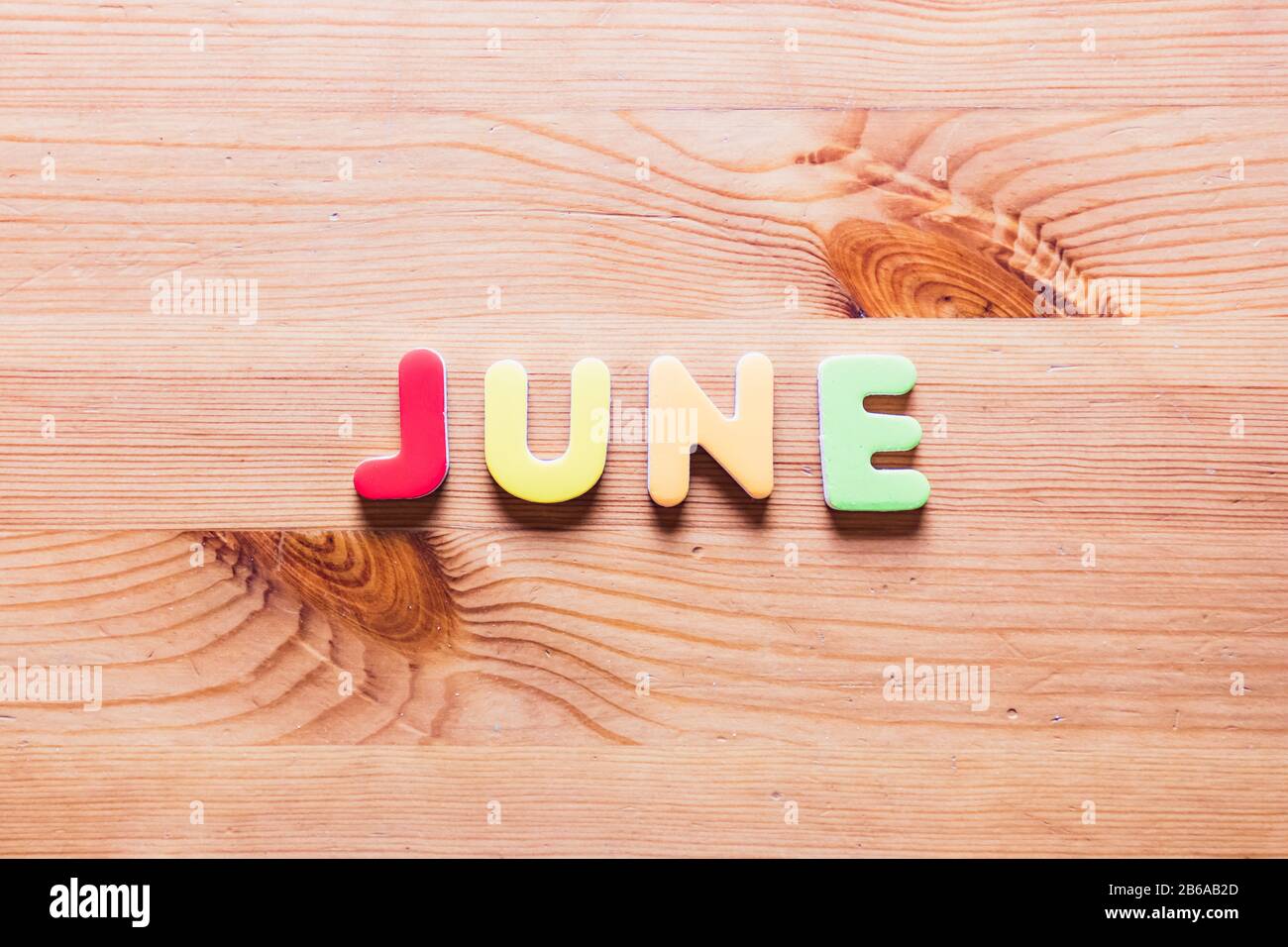 June word written with colorful letters on wooden background, top view ...